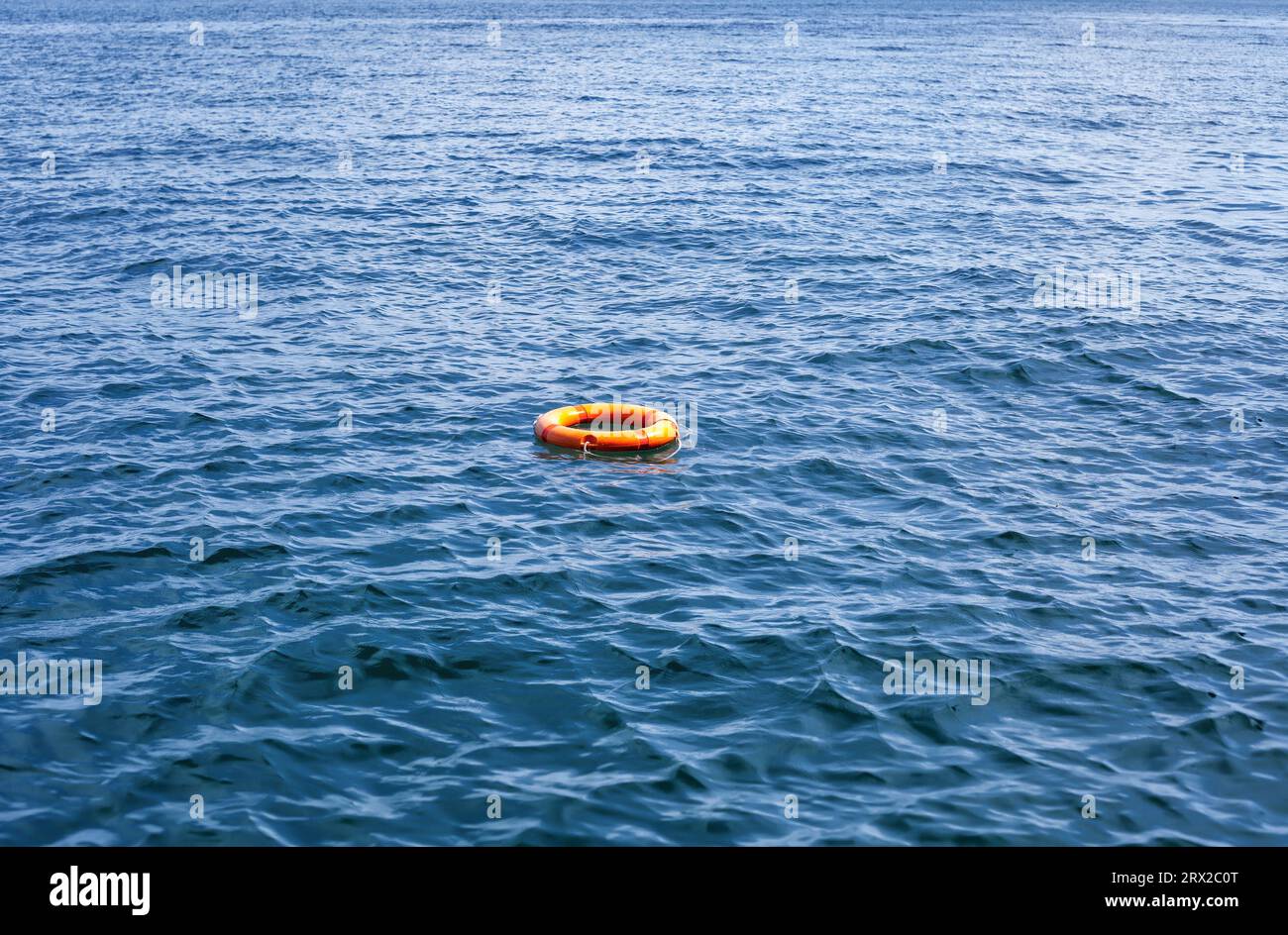 Orange life buoy floating in vast expanse of sea. Red lifebuoy float on ...