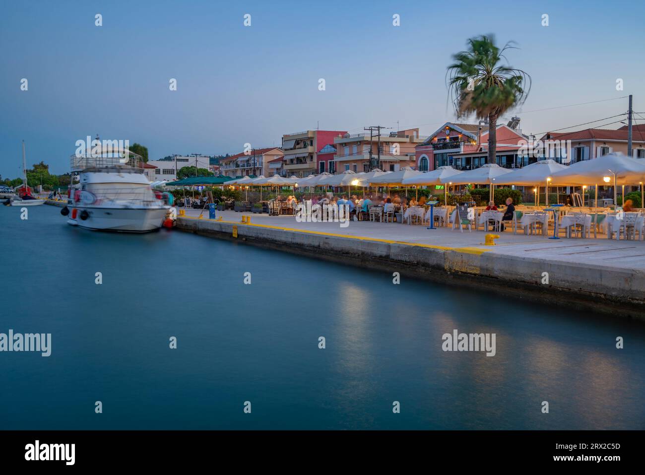 View of cafe and restaurant at the harbour at dusk, Lixouri, Kefalonia ...