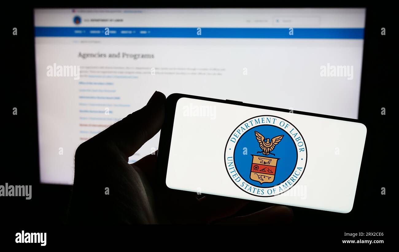 Person holding smartphone with seal of United States Department of ...