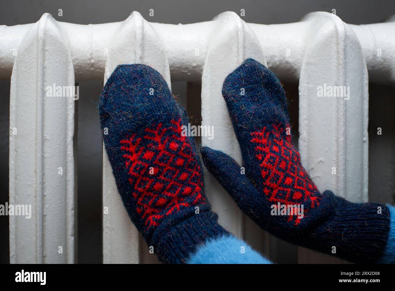 Human warming up hands in mittens near Hot Water Radiator. Space for ...