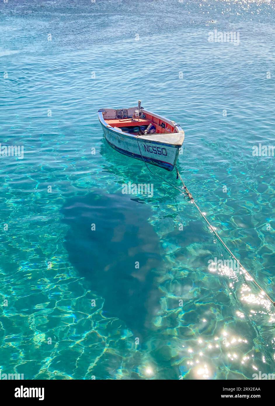 Weathered rowboat with Pelican resting in very clear Caribbean waters ...