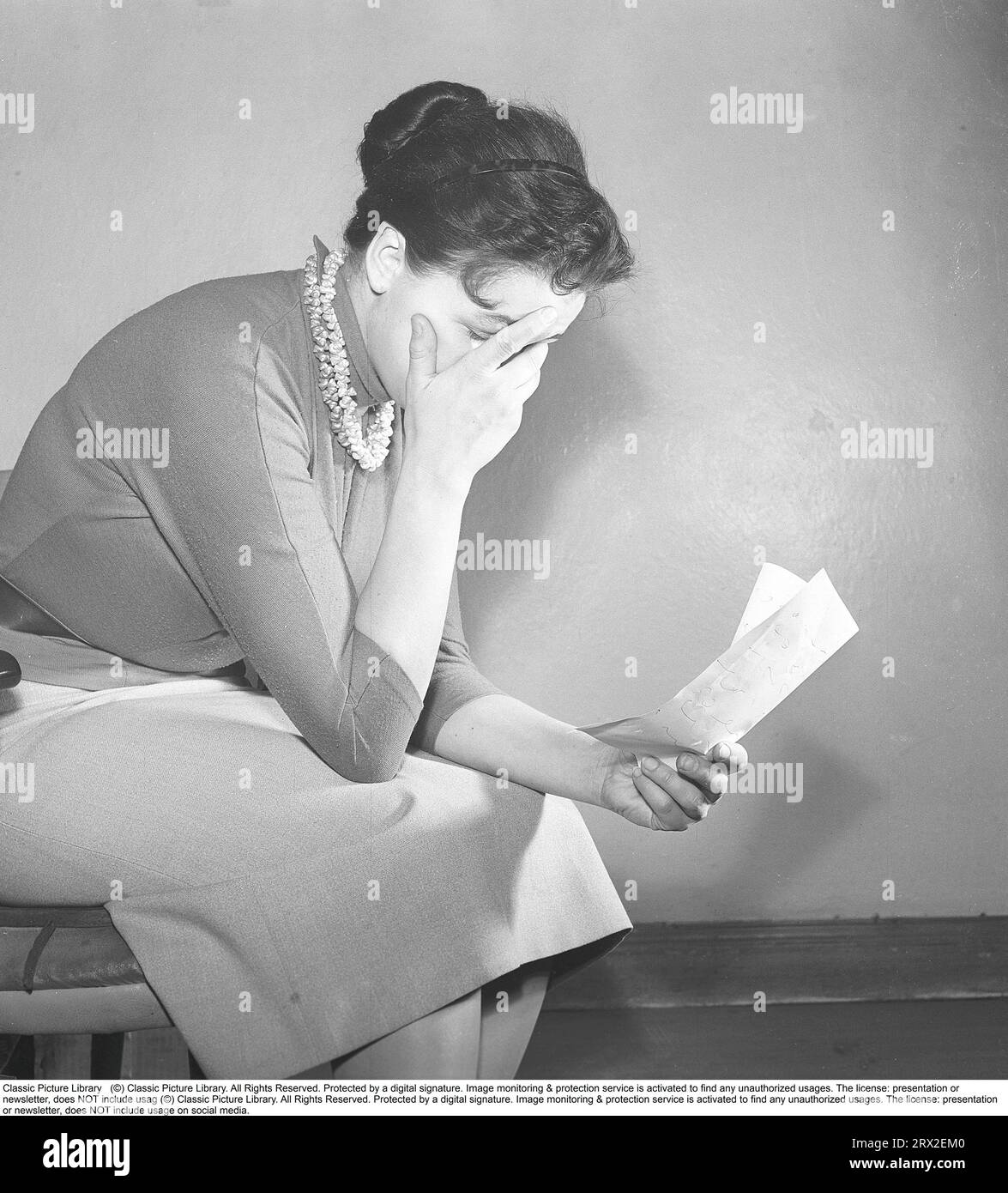 Woman in the 1950s. A woman has read a letter and sits sorrowfully ...