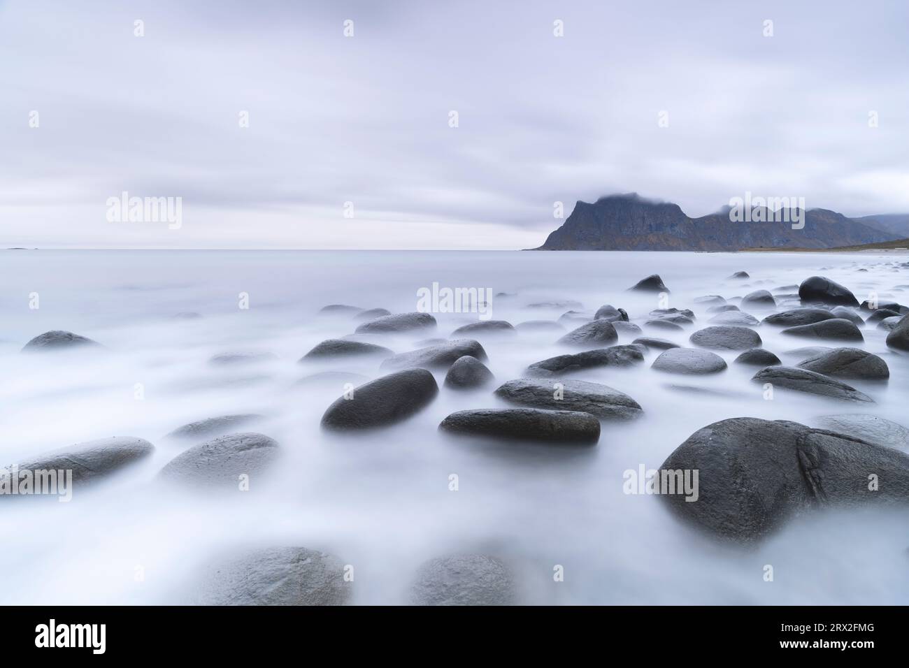 Clouds at dusk over rocks washed by the Arctic sea at Uttakleiv beach ...