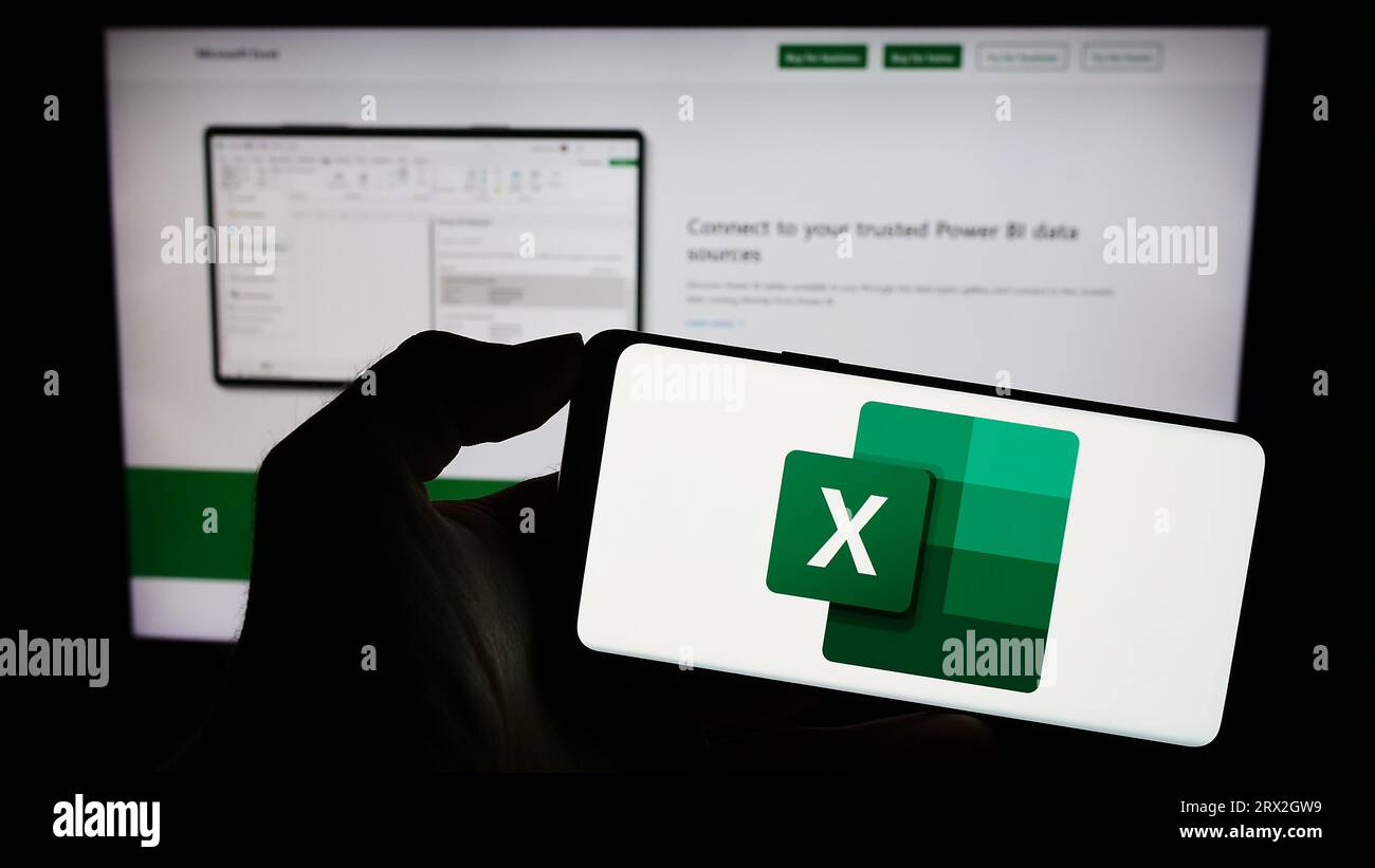 Person holding mobile phone with logo of spreadsheet editor Microsoft Excel on screen in front ...