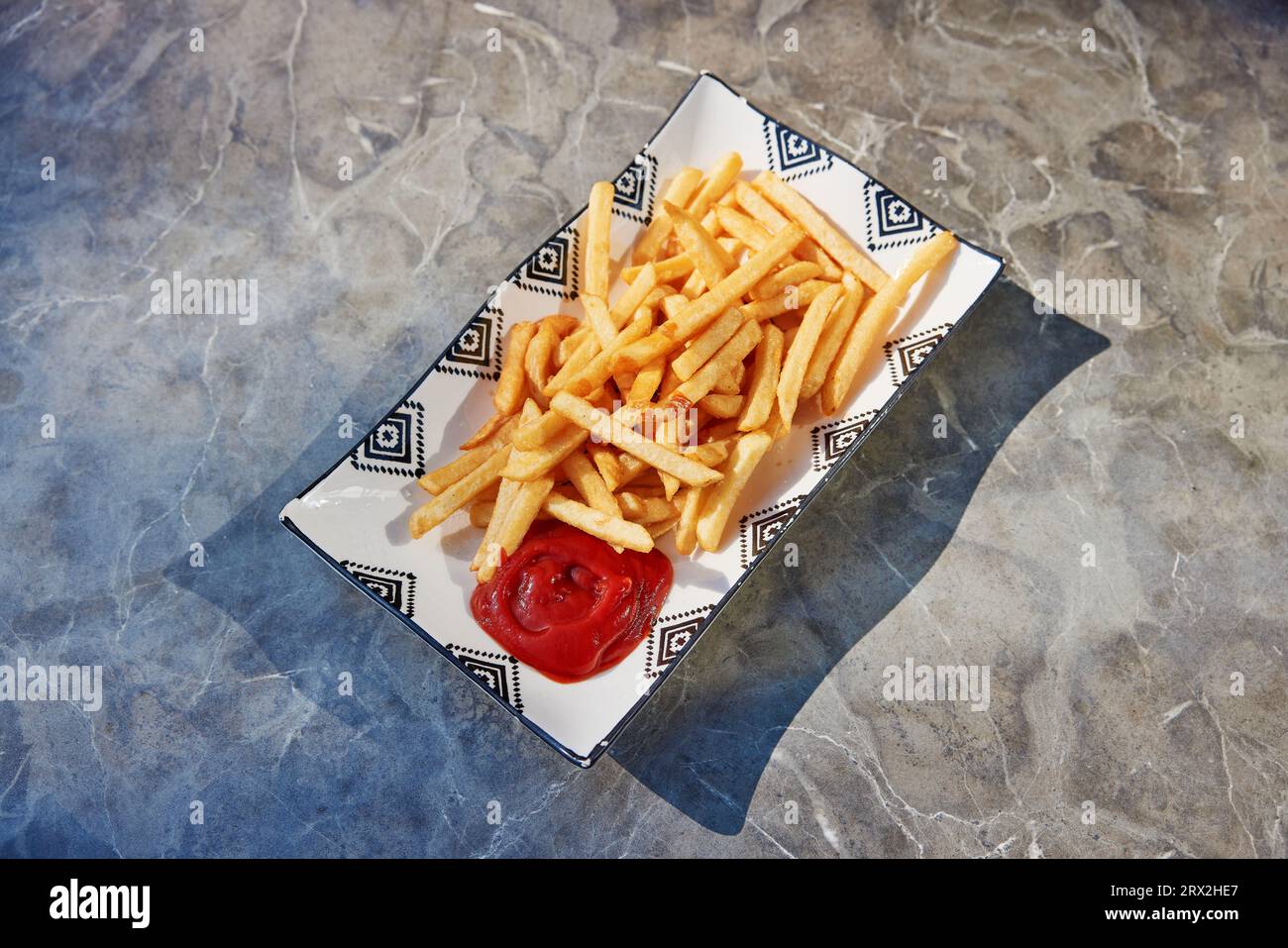 French fries with ketchup, rectangular plate on marbled table top Stock ...