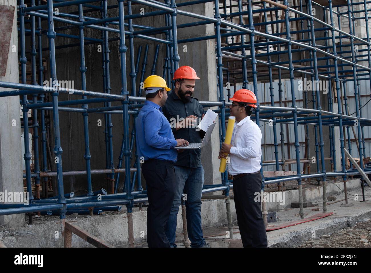 Team of three male construction engineers wearing safety hardhats ...