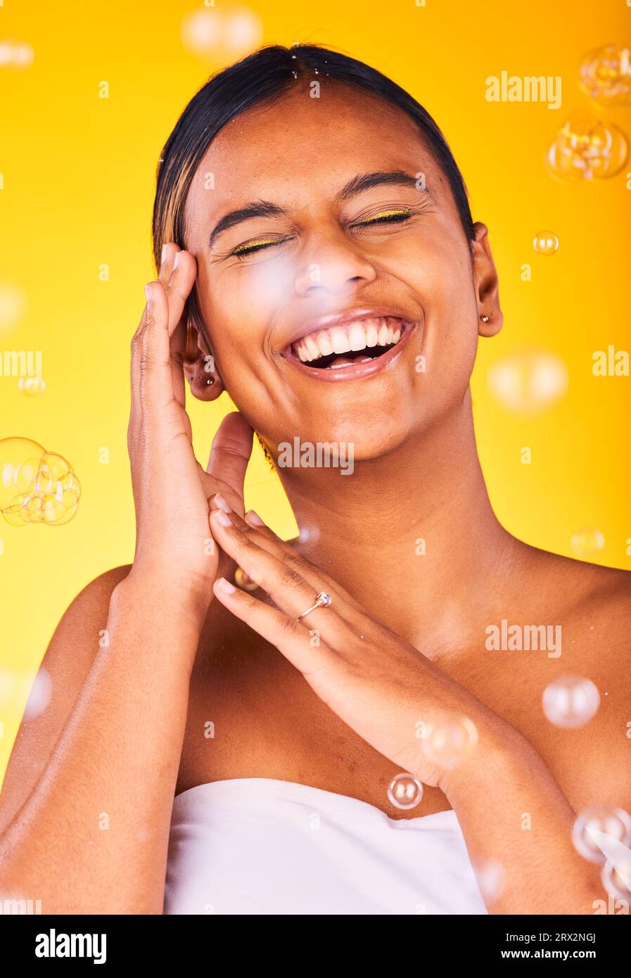 Face, beauty and bubbles with a woman laughing on a yellow background ...