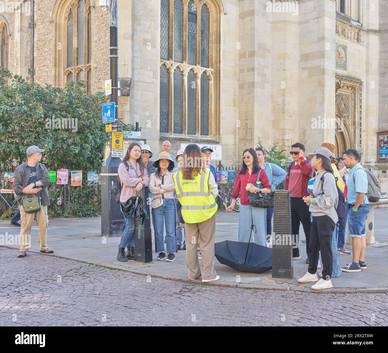 Mixed party of tourists with guide outside the University of Cambridge ...