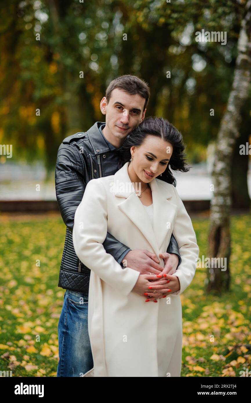 A man hugs his pregnant wife. A man in a black jacket hugs a woman in a ...