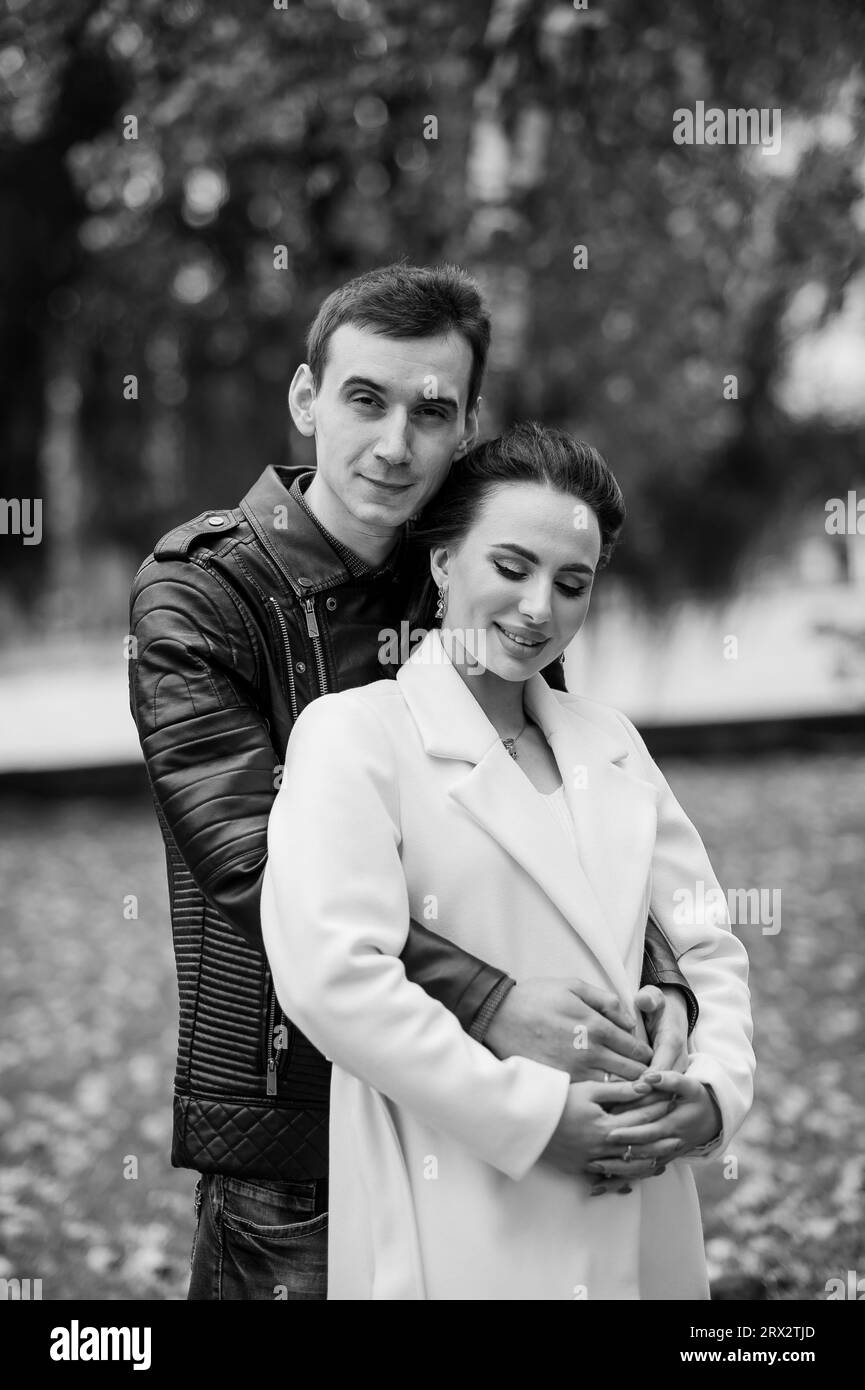 A man hugs his pregnant wife. A man in a black jacket hugs a woman in a ...