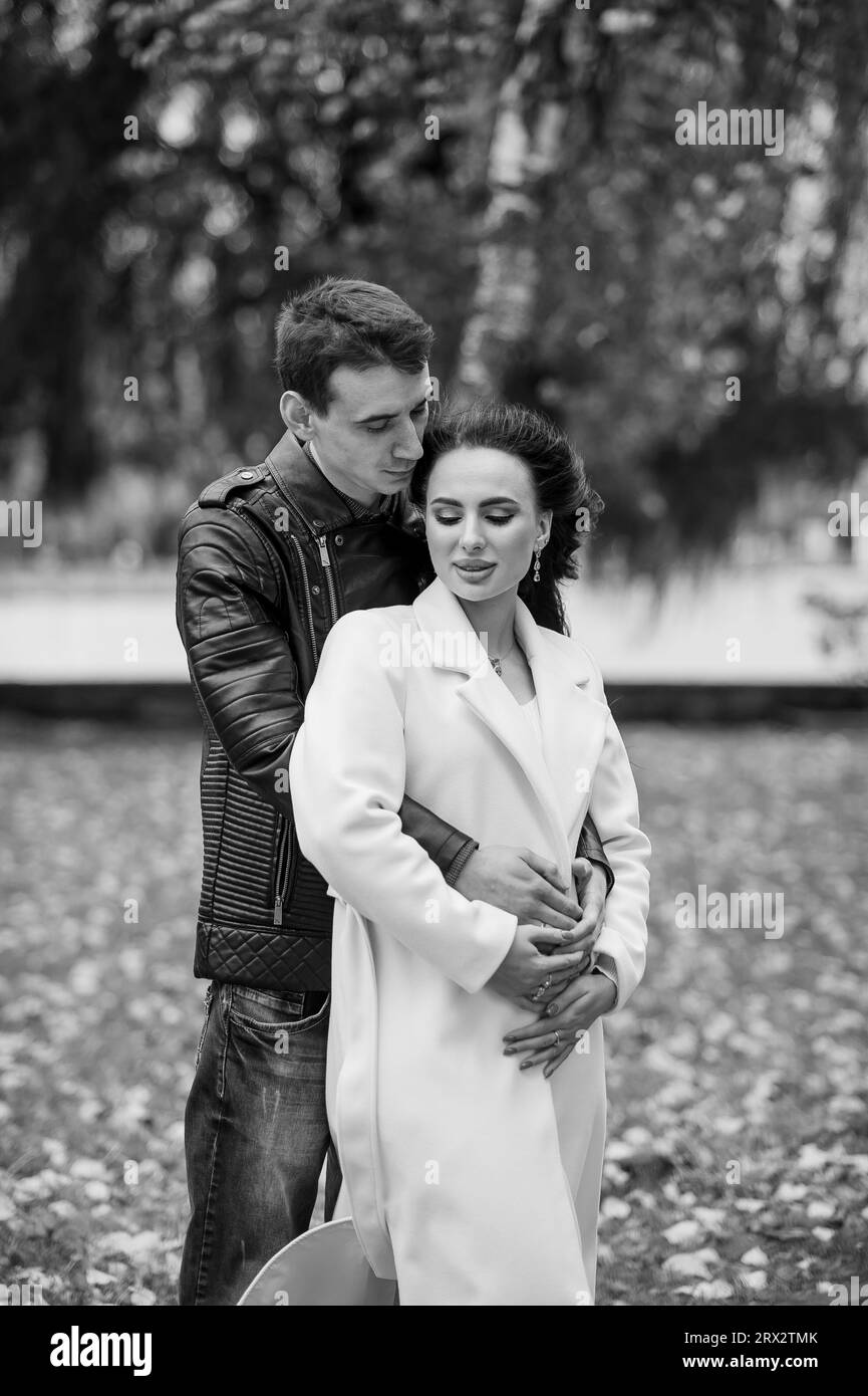 A man hugs his pregnant wife. A man in a black jacket hugs a woman in a ...
