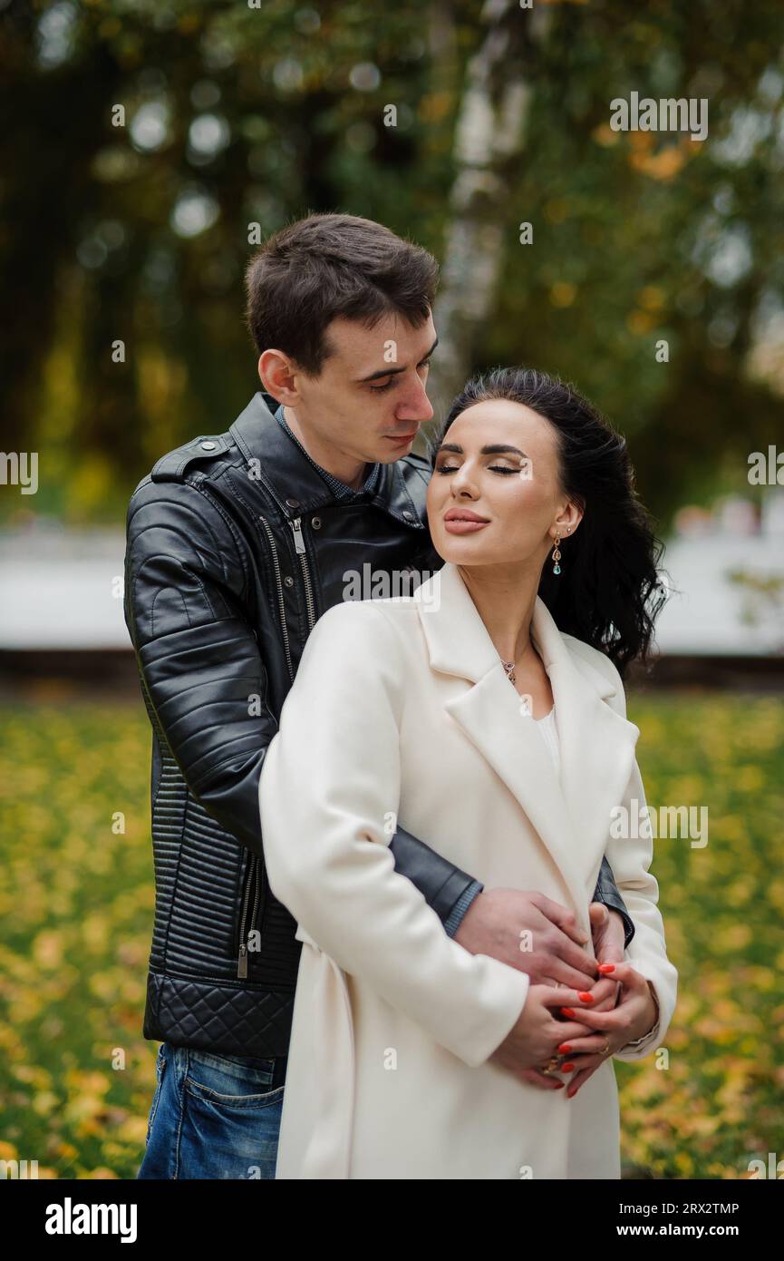 A man hugs his pregnant wife. A man in a black jacket hugs a woman in a ...