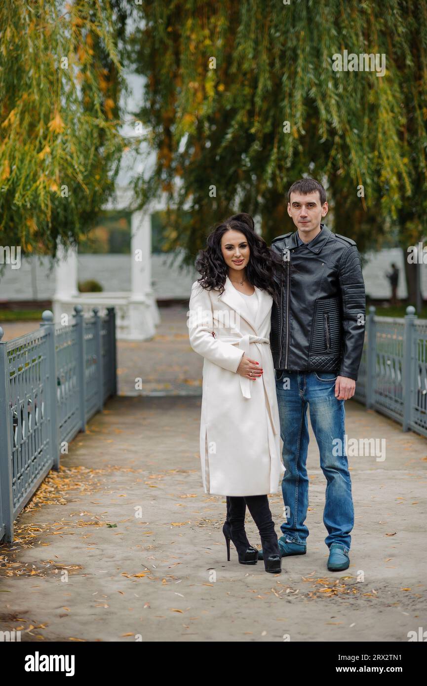 A man hugs his pregnant wife. A man in a black jacket hugs a woman in a ...