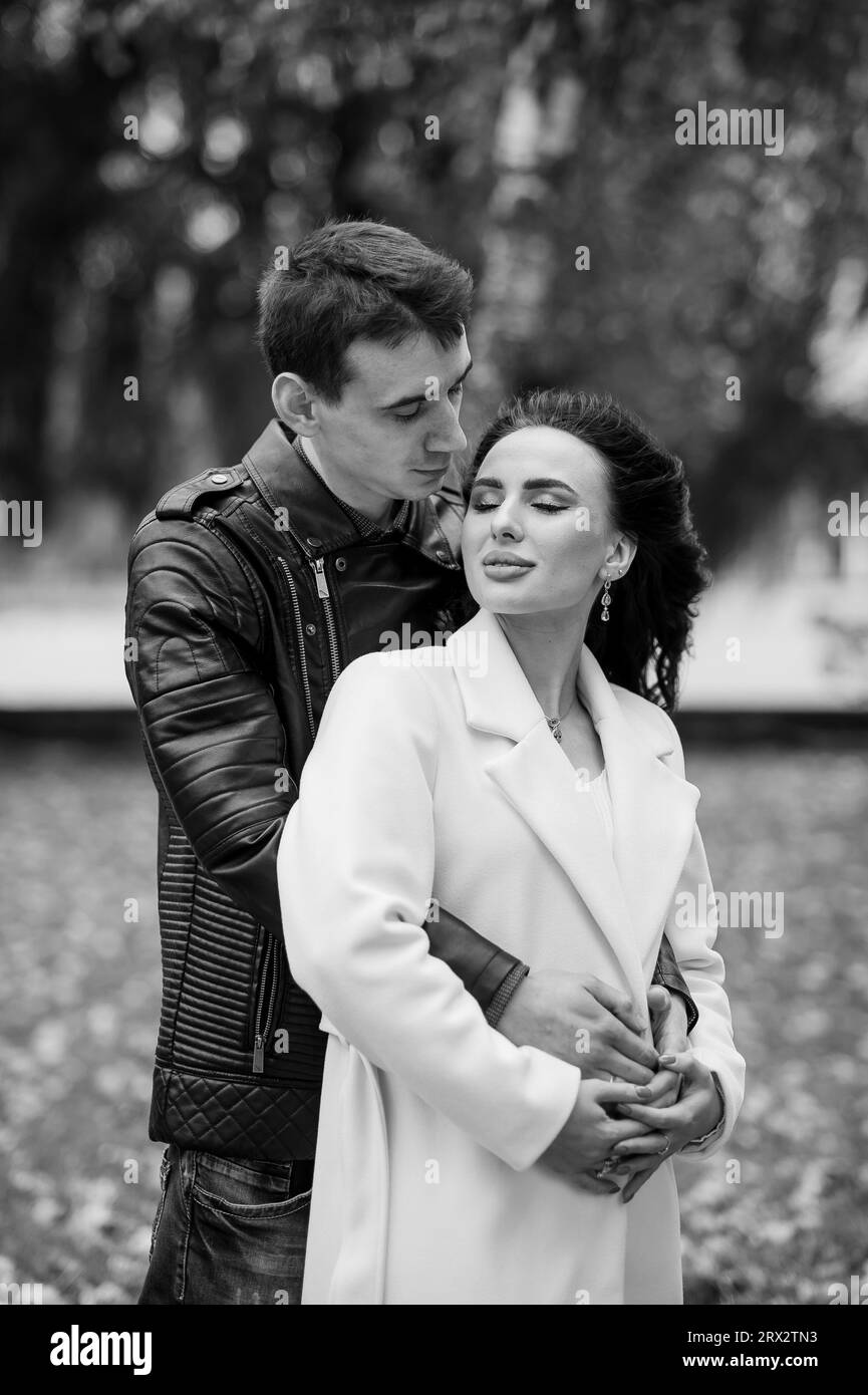 A man hugs his pregnant wife. A man in a black jacket hugs a woman in a ...