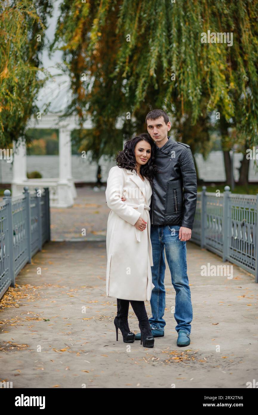 A man hugs his pregnant wife. A man in a black jacket hugs a woman in a ...