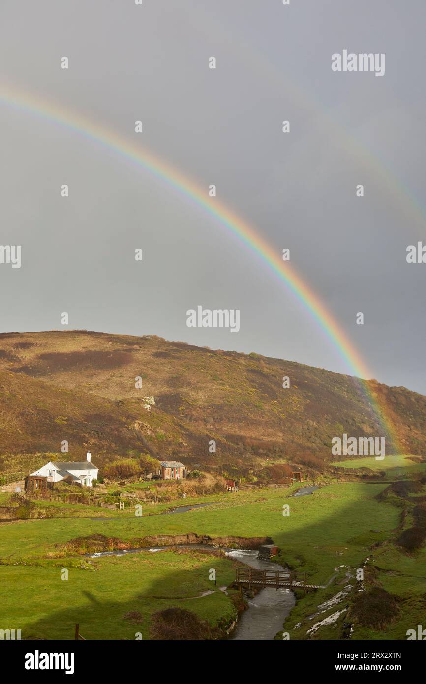 A valley rainbow forms in the face of an autumn squall, in Duckpool, a ...