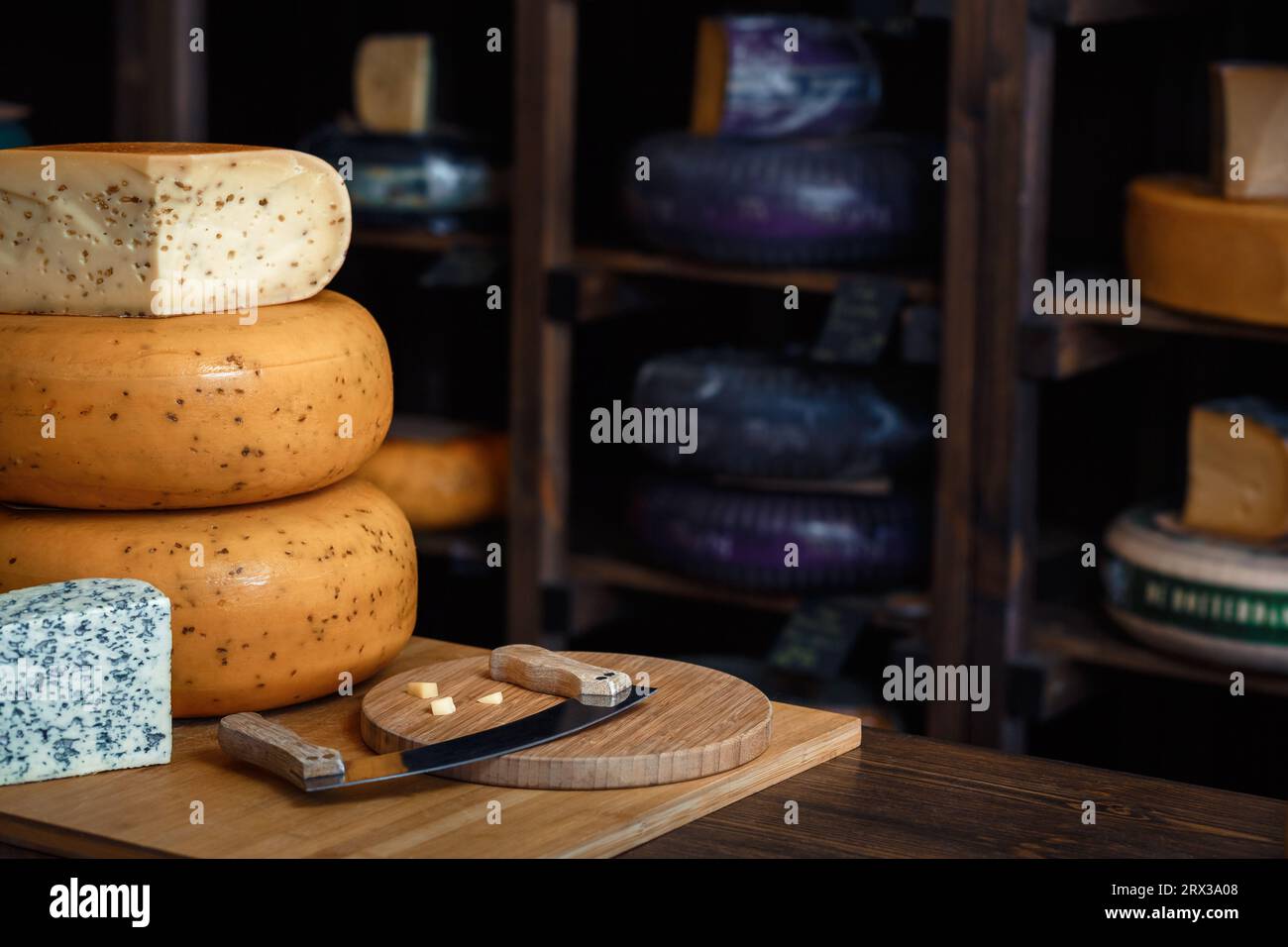 Cheese heads with slices and knives lie on a wooden board with an ...