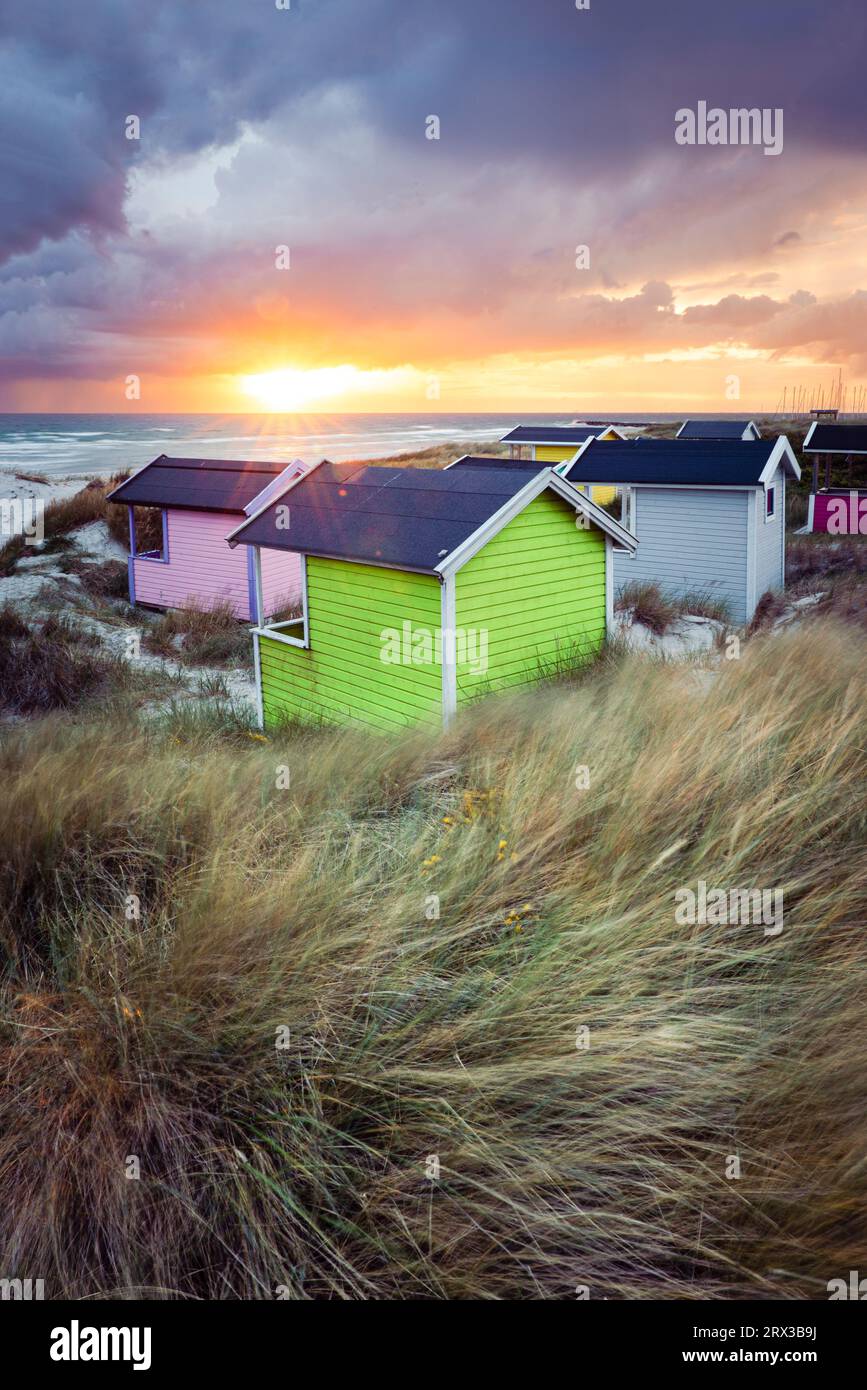 Wind and clouds at sunset over the colourful bathing huts in the sand ...