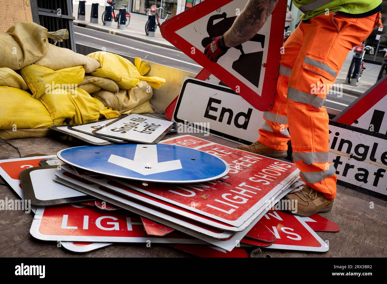 After temporary roadworks, a contractor sorts and stacks road signs and ...