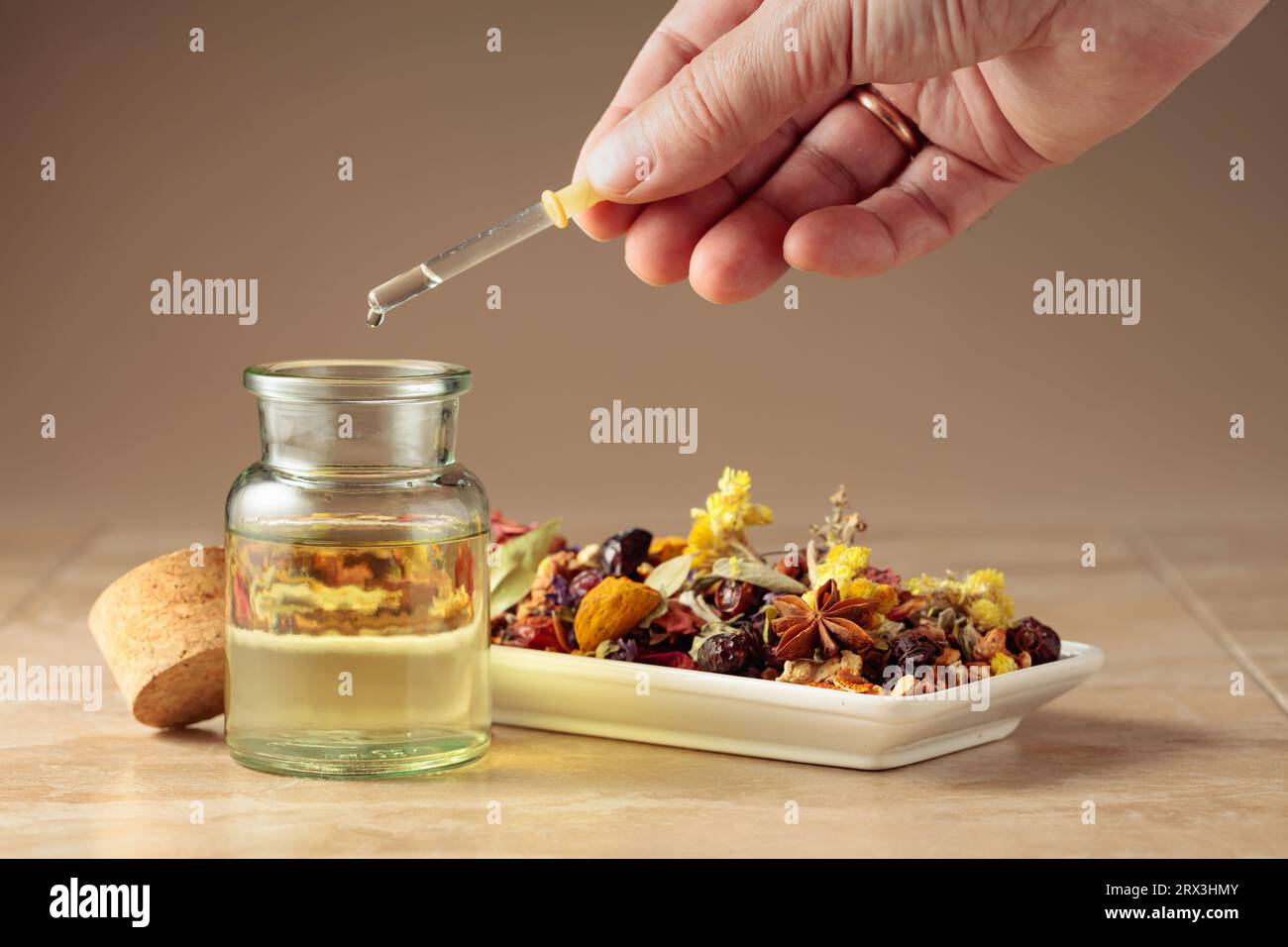 Dropping essential oil or herbal tincture into a glass bottle. Mix of ...