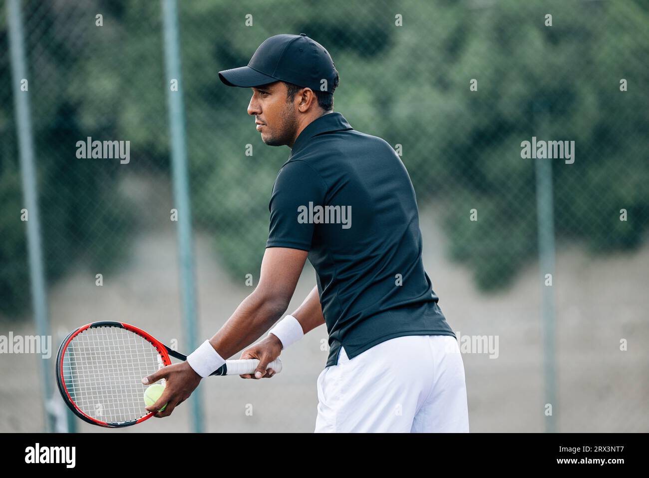 Side view of a professional tennis player holding a racket and ball ...