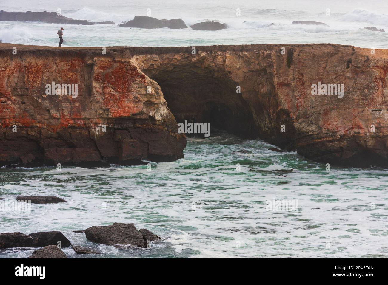 Photographer on cliff at Point Arena peninsula with storm coming in ...