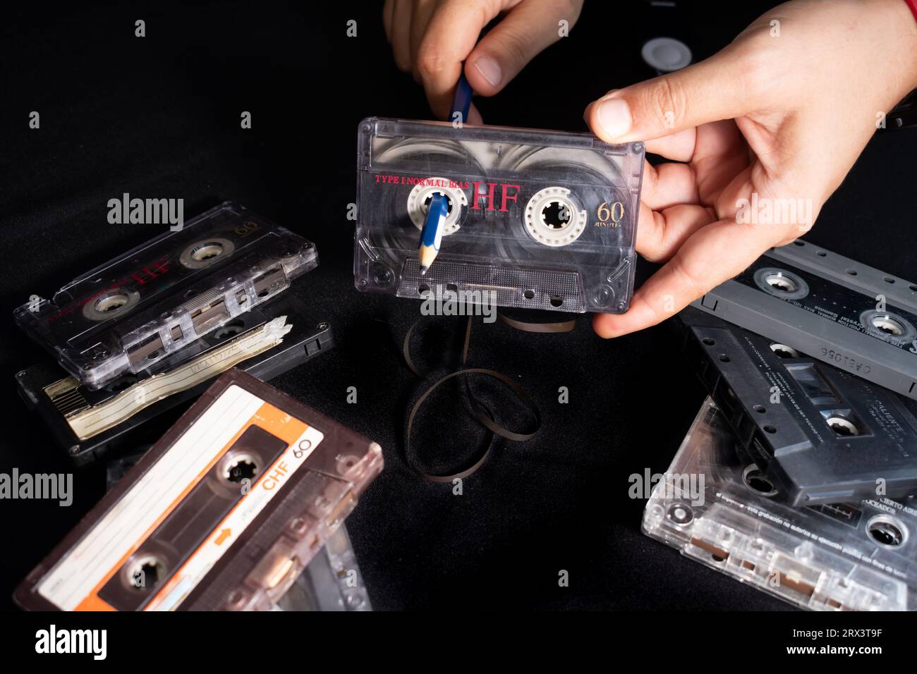 Nostalgia. Person using a pencil to wind the tape of a retro cassette ...