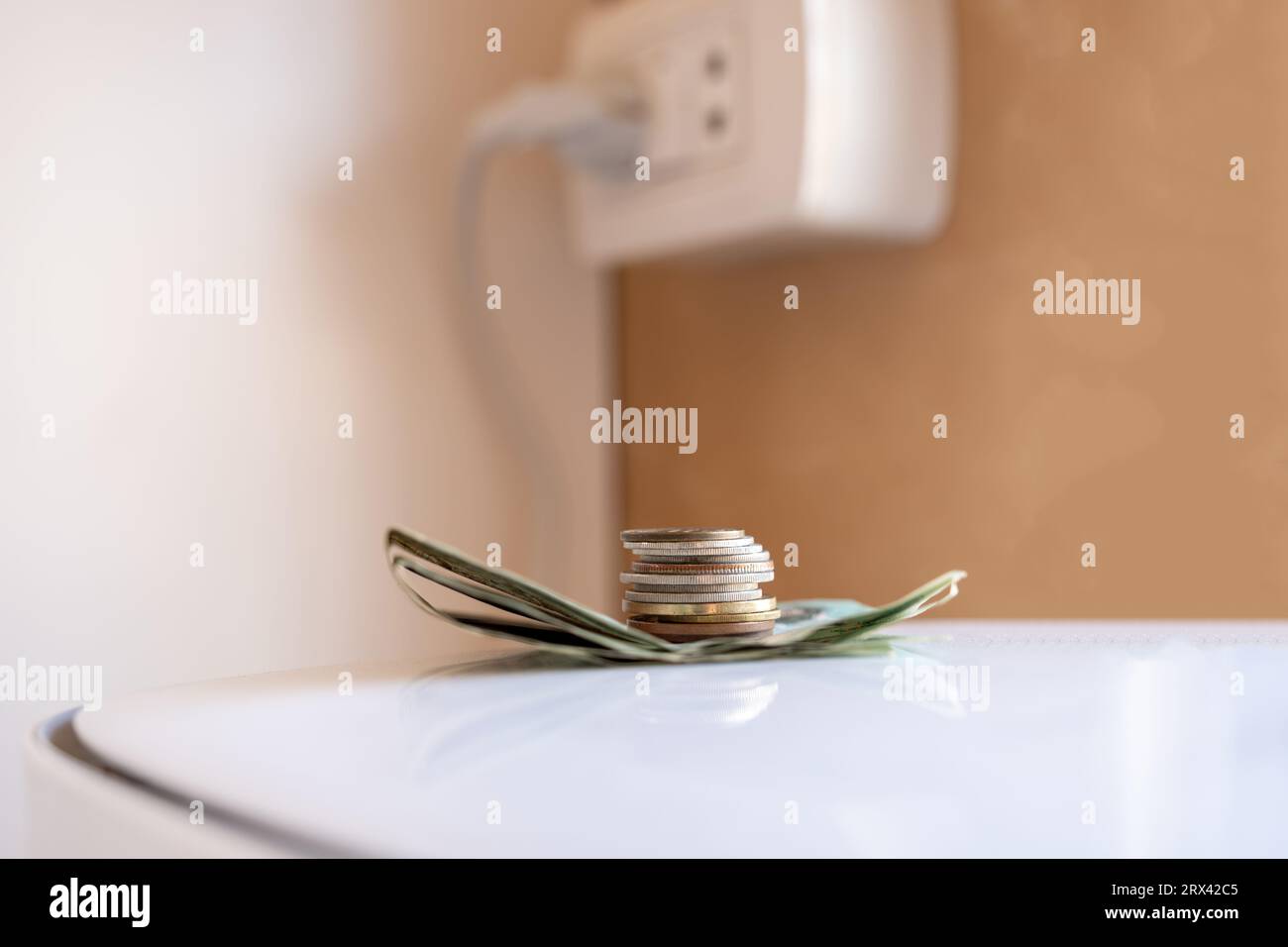 money with electric cord and socket in the background represents costs ...