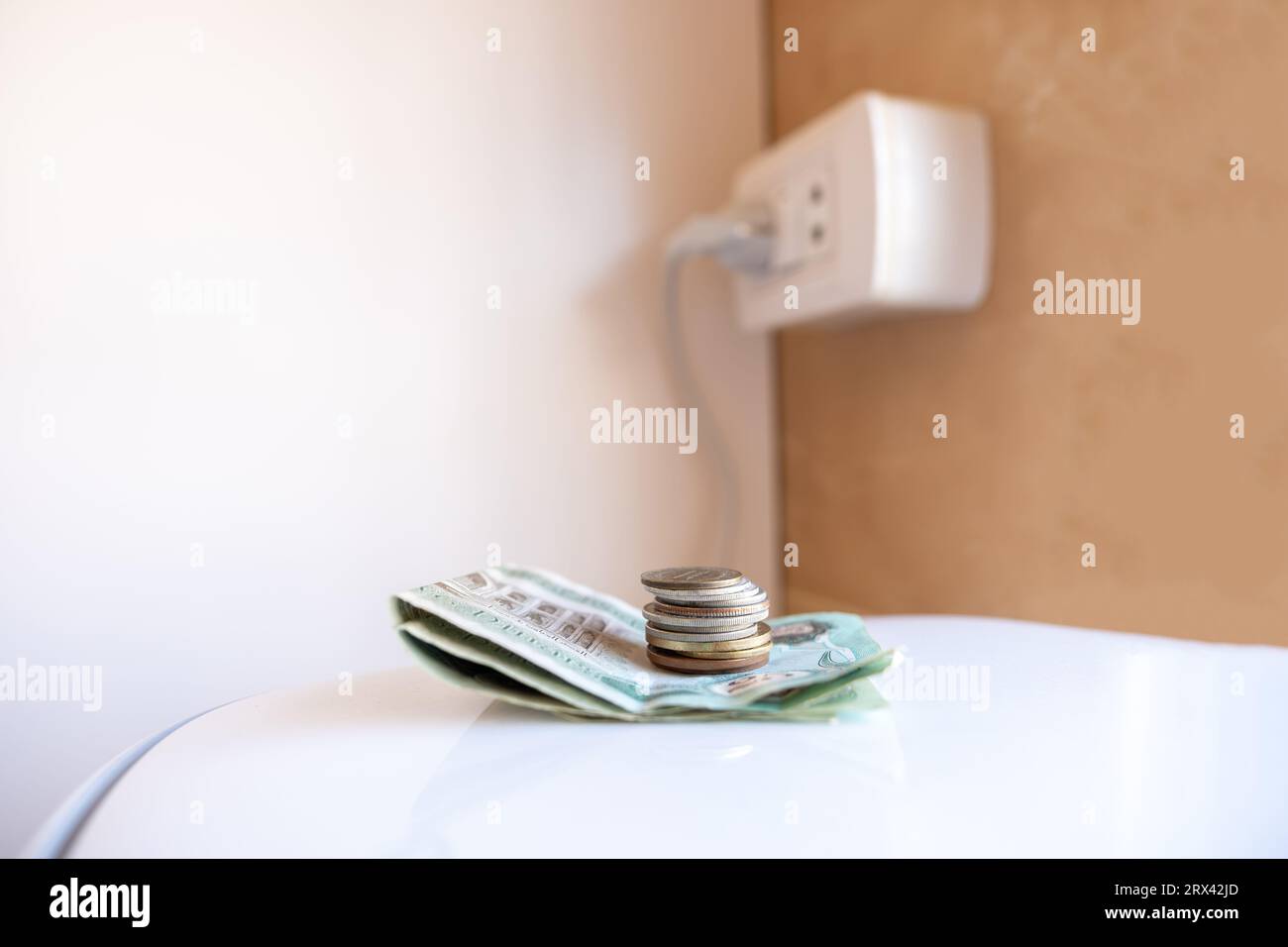 money with electric cord and socket in the background represents costs ...