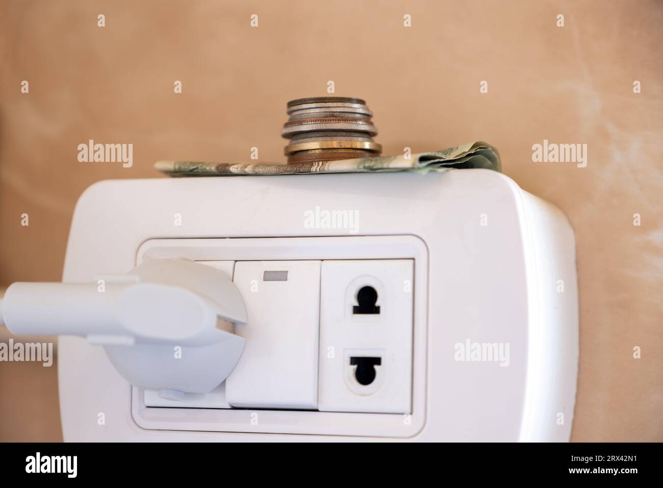 money with electric cord and socket in the background represents costs ...