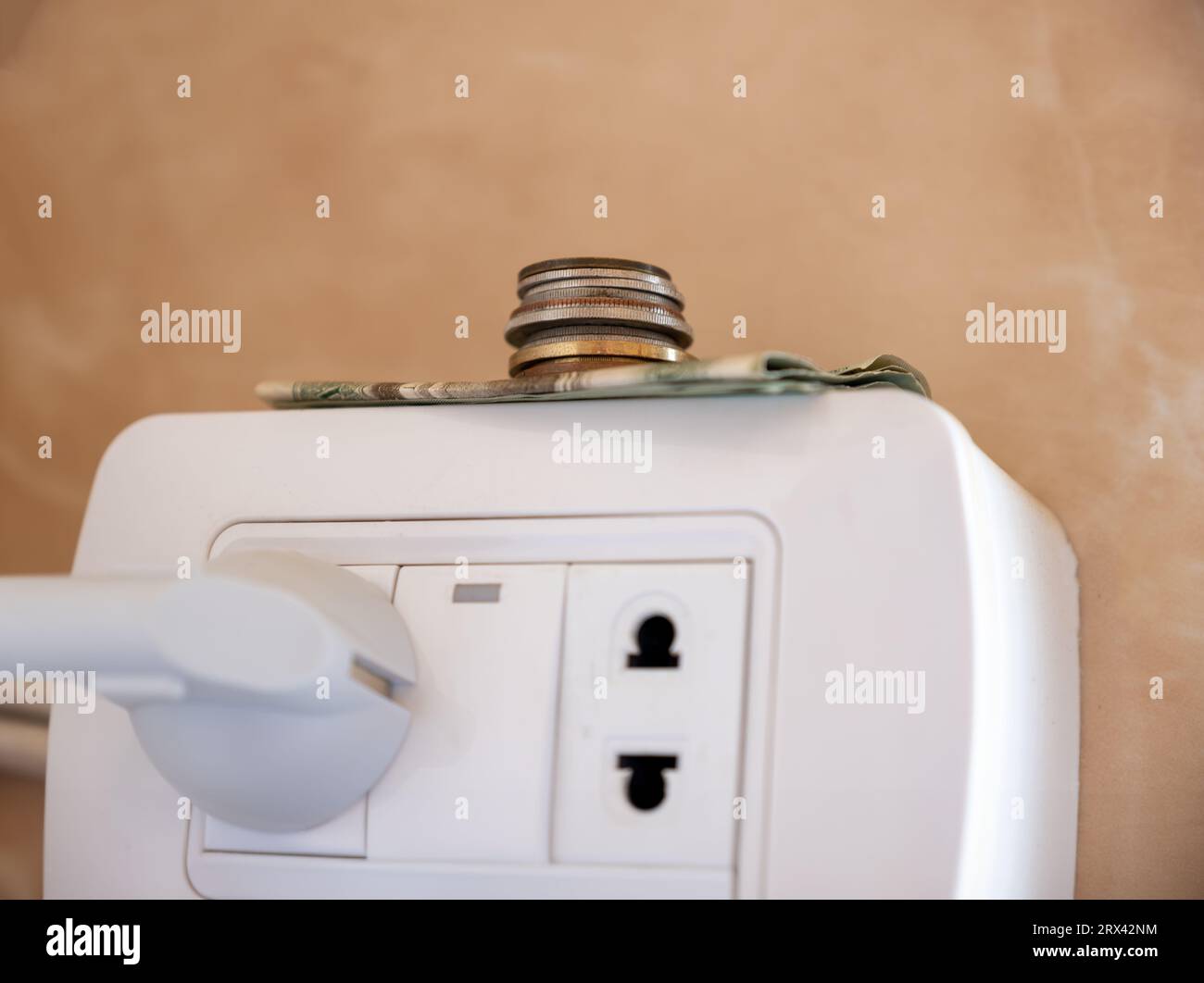 money with electric cord and socket in the background represents costs ...