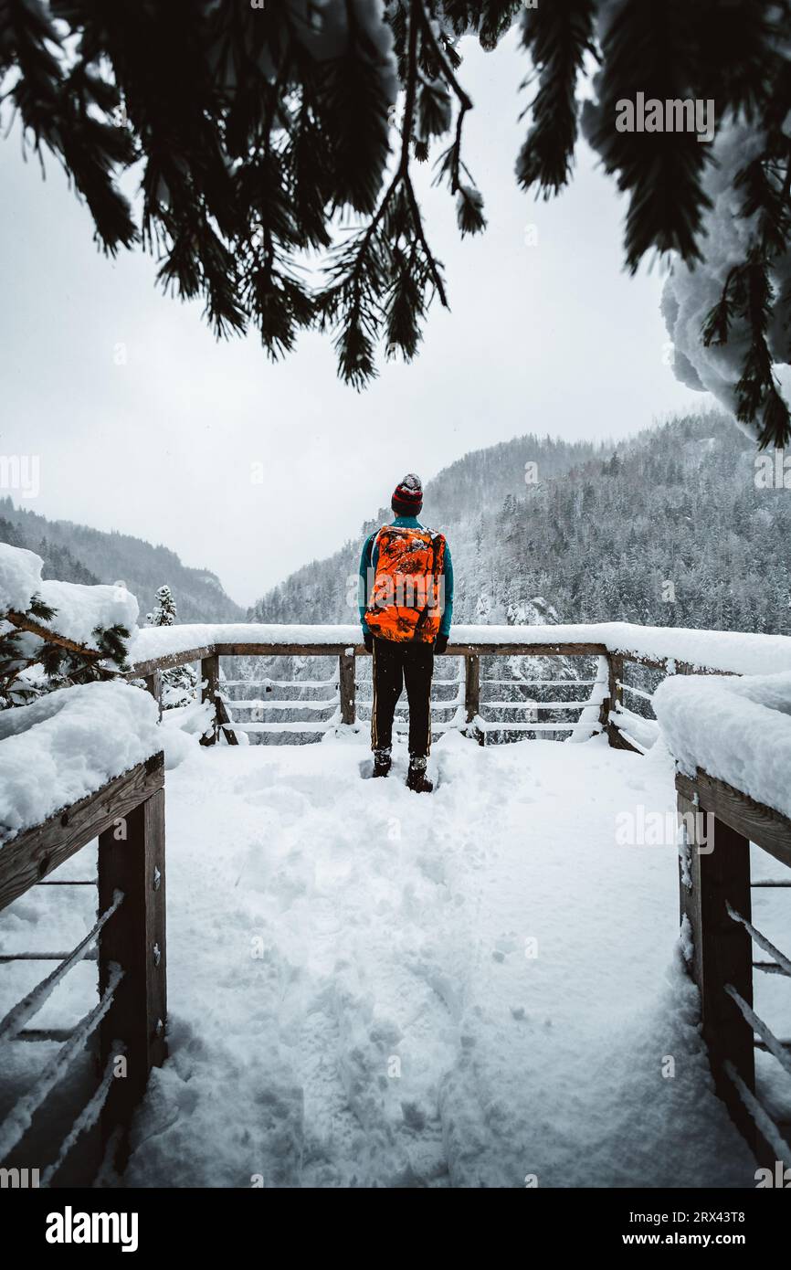 Man tourist and climber with orange backpack standing on the outlook ...