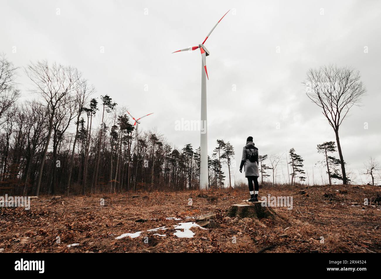 Woman standing and looking on wind turbine station in destroyed and ...