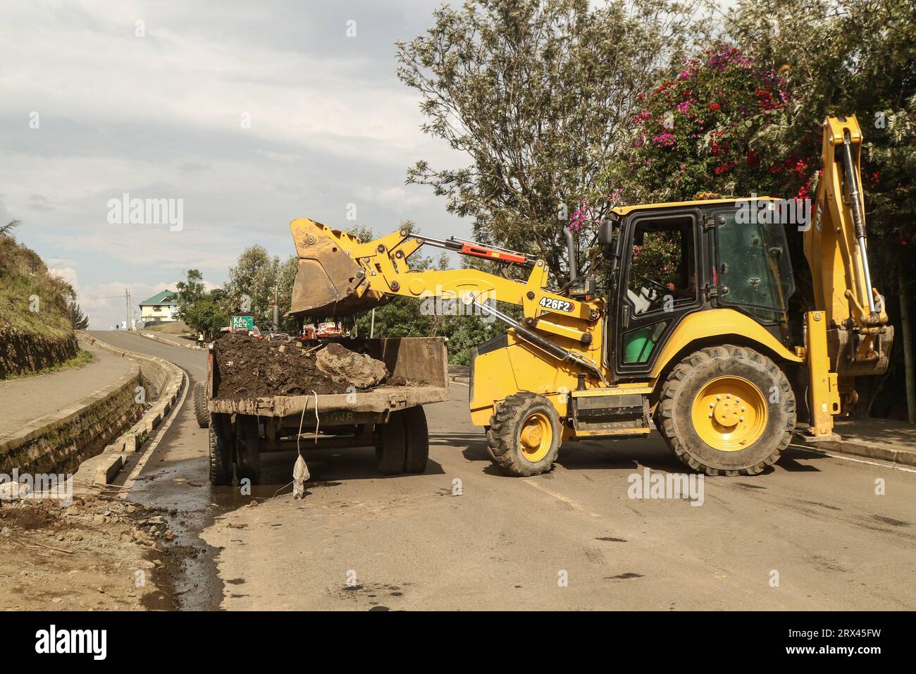 An excavator loads debris collected from a channel and pours it onto a ...