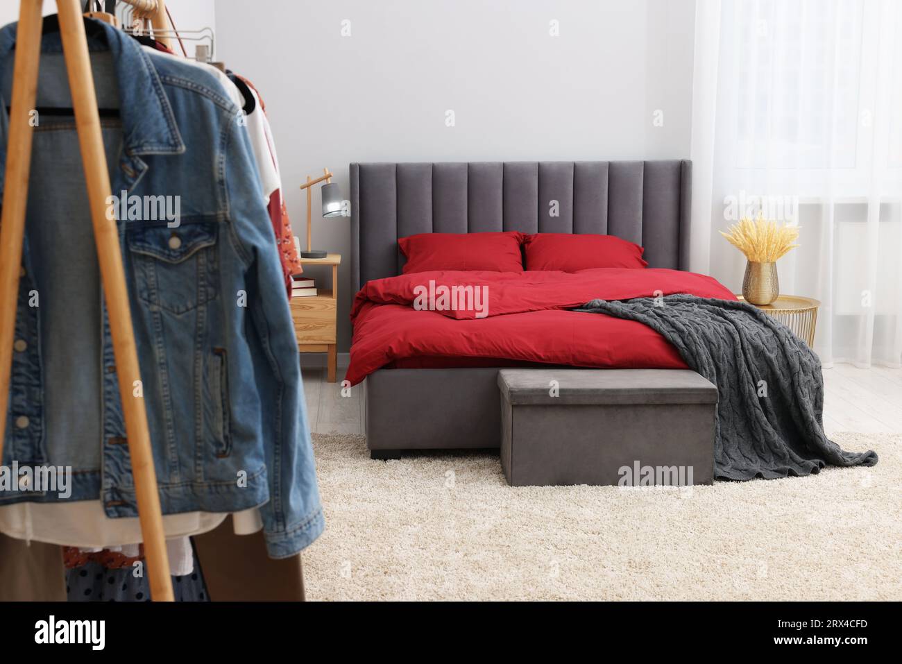 Stylish bedroom with comfortable bed and clothing rack. Interior design ...