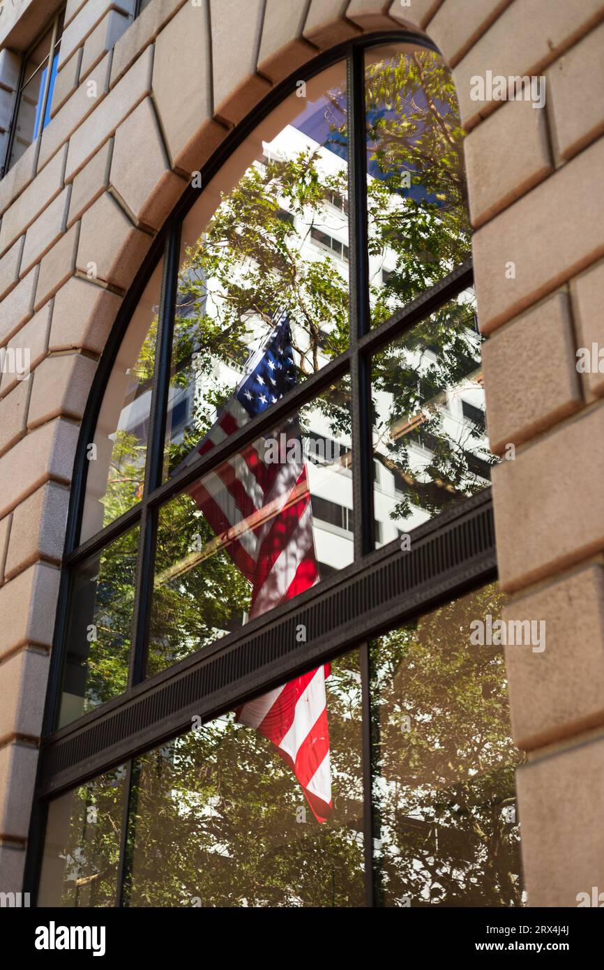 Reflection of an American flag in the window of a brick building Stock ...