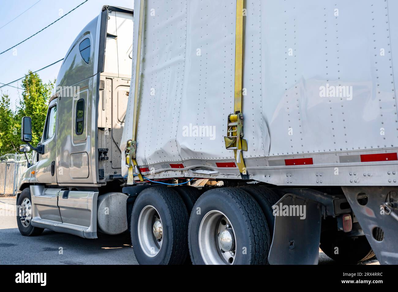 Beige industrial grade big rig semi truck tractor with broken dry van ...