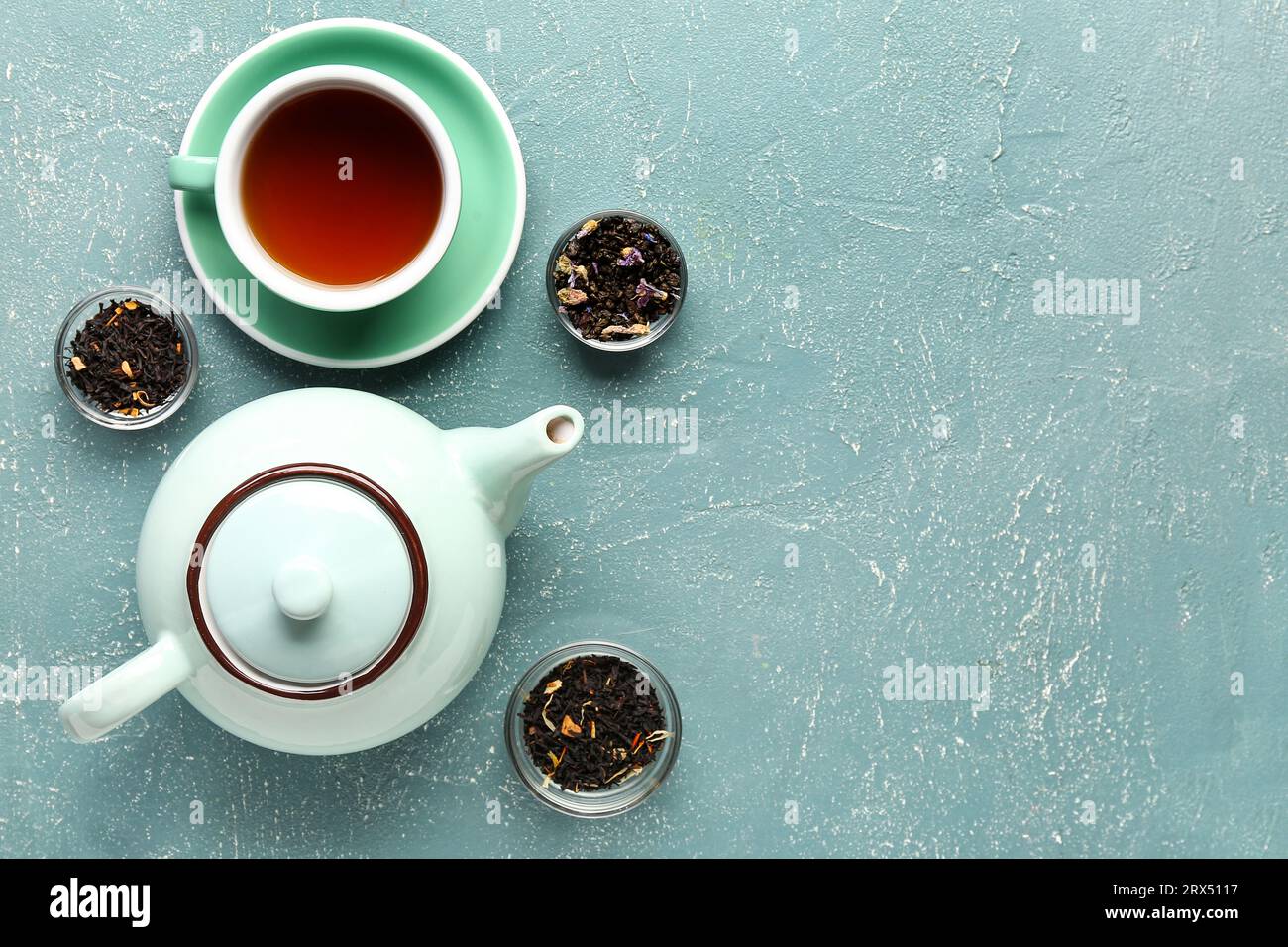 Teapot, different types of tea and cup of beverage on color background ...