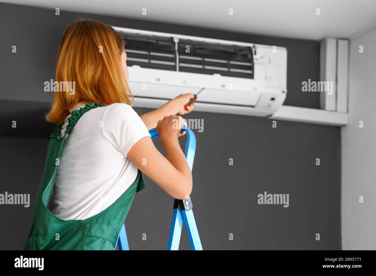 Female technician fixing air conditioner in room Stock Photo - Alamy
