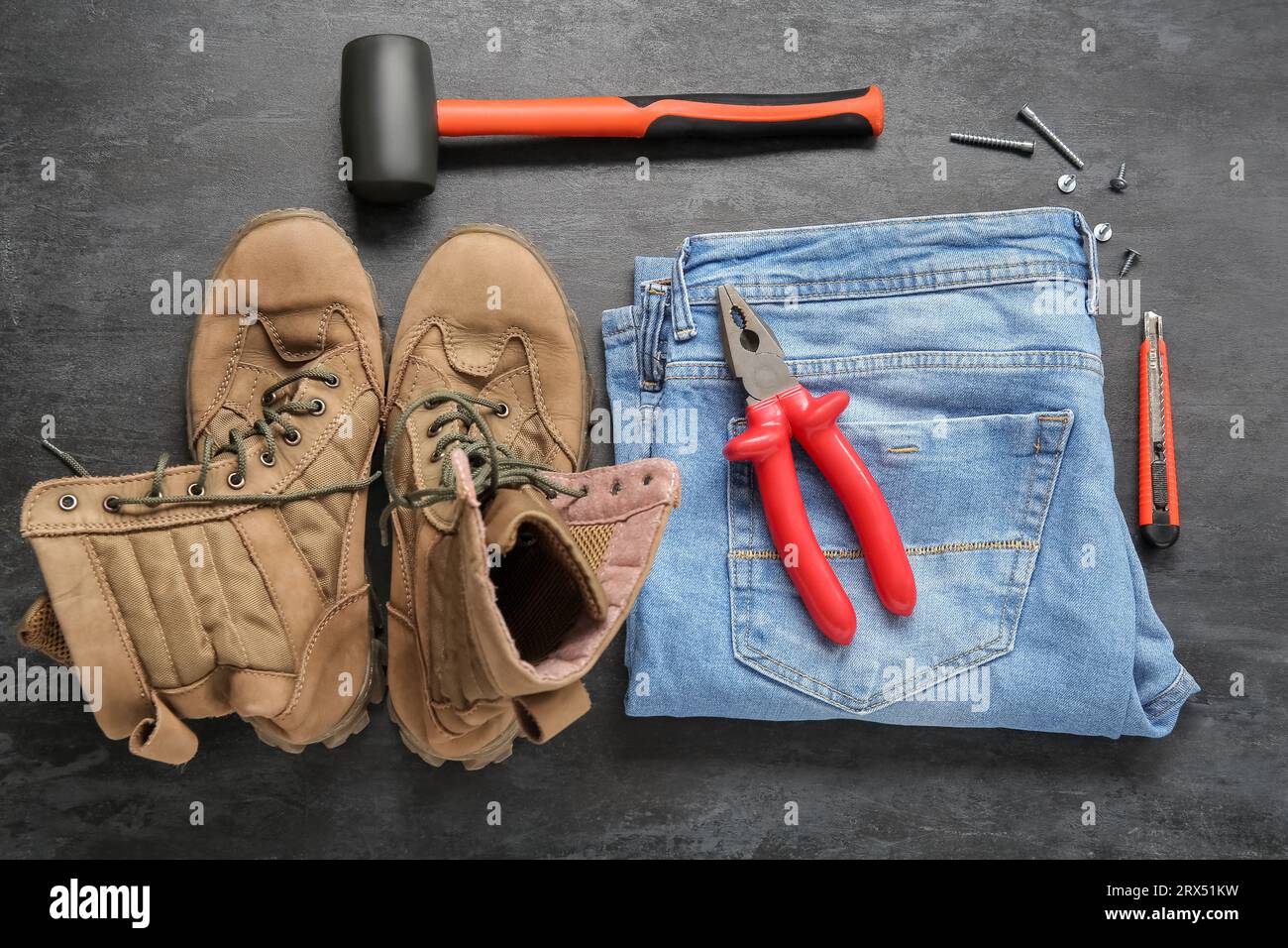Pair of work boots, jeans and different tools on black grunge ...
