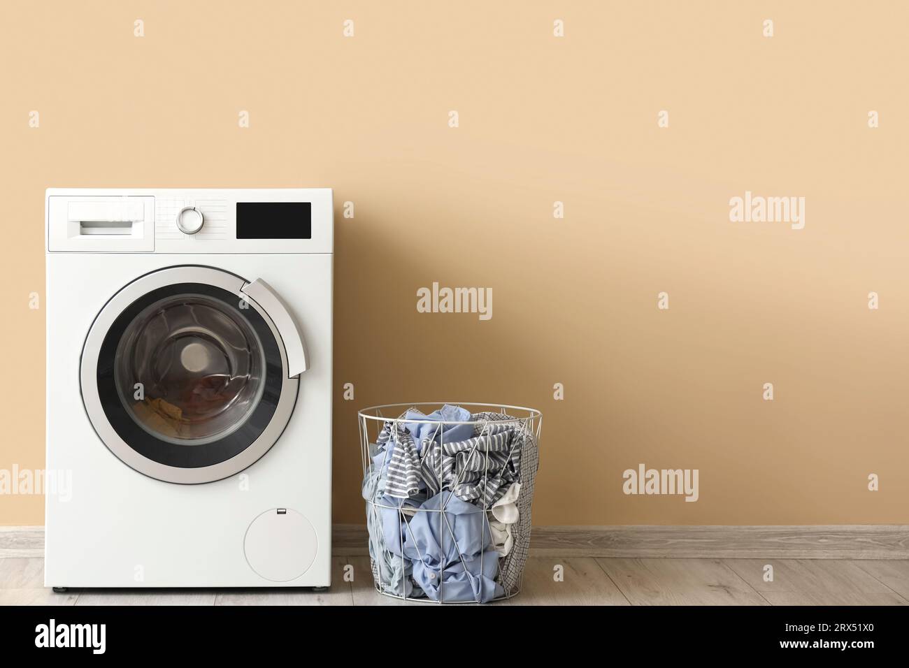 Modern washing machine with laundry basket near beige wall Stock Photo ...