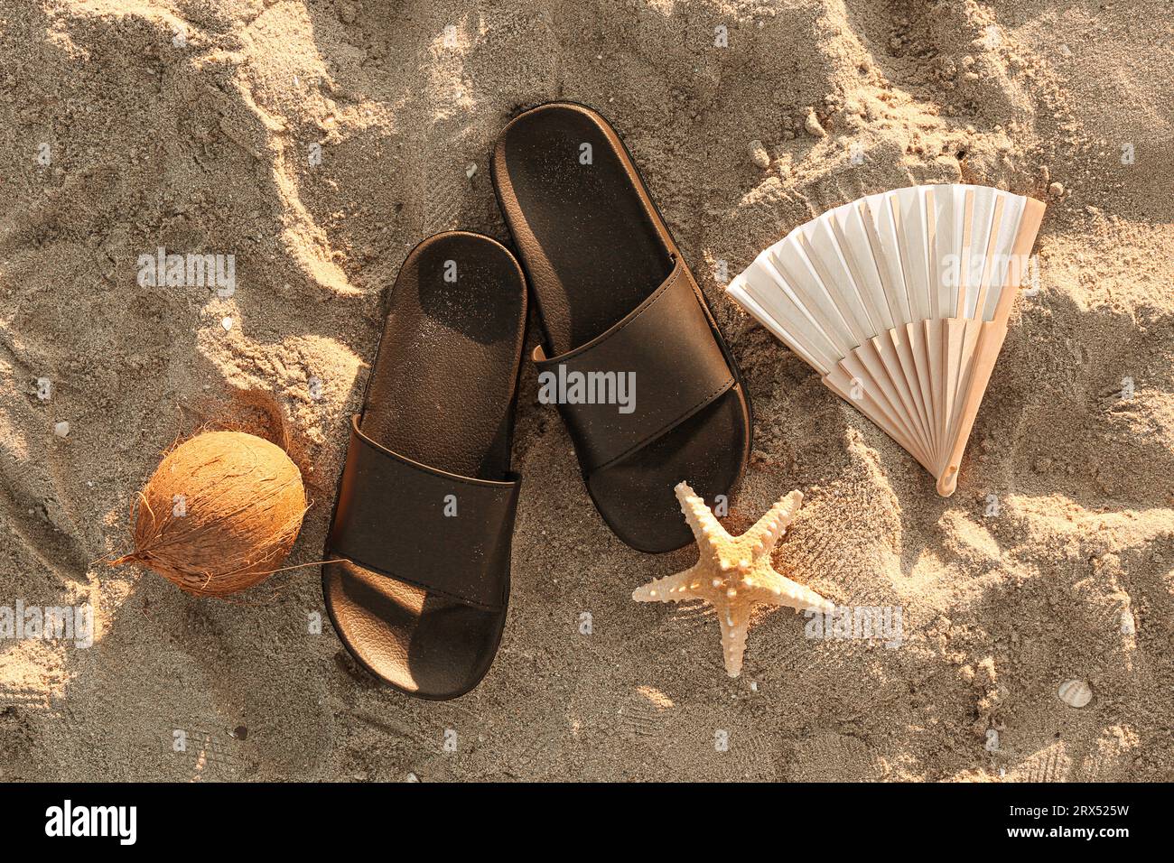 Stylish female flip flops, fan, starfish and coconut on sand Stock ...