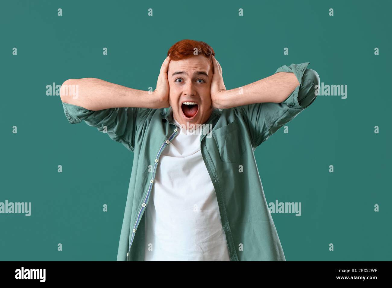 Fearful young man screaming on green background Stock Photo - Alamy