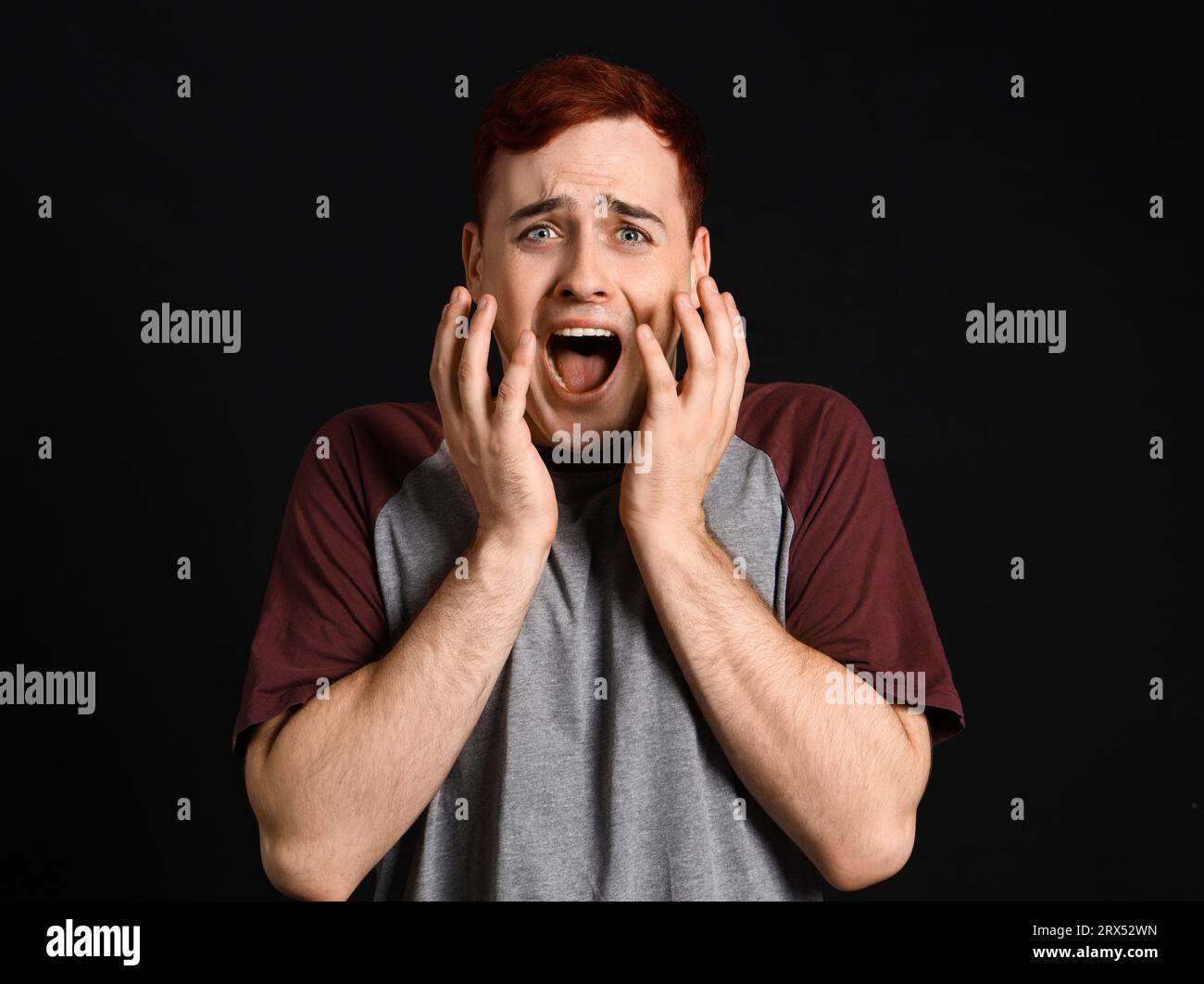 Fearful young man screaming on black background Stock Photo - Alamy