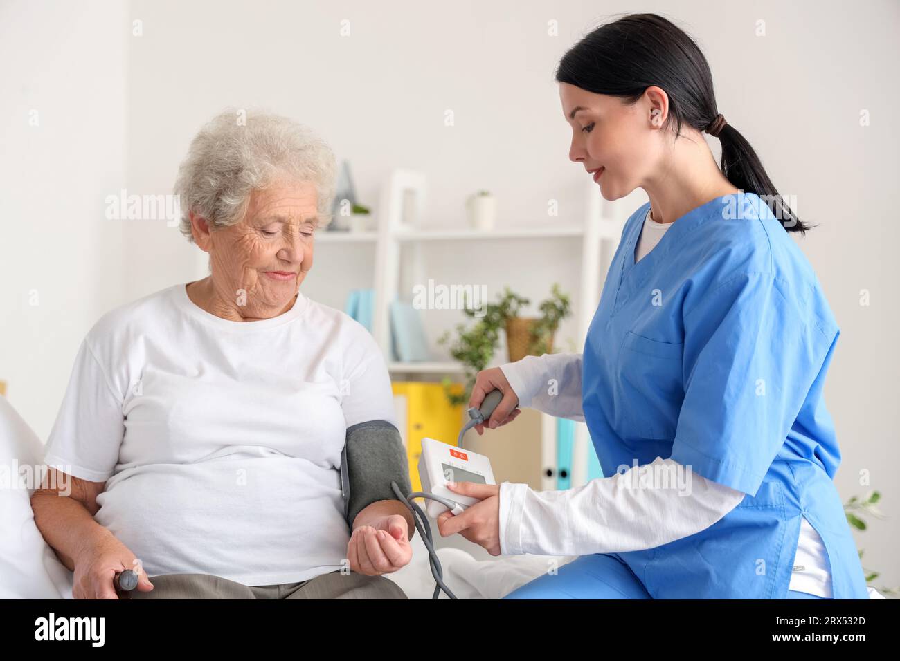 Female nurse measuring blood pressure of senior woman in bedroom Stock ...