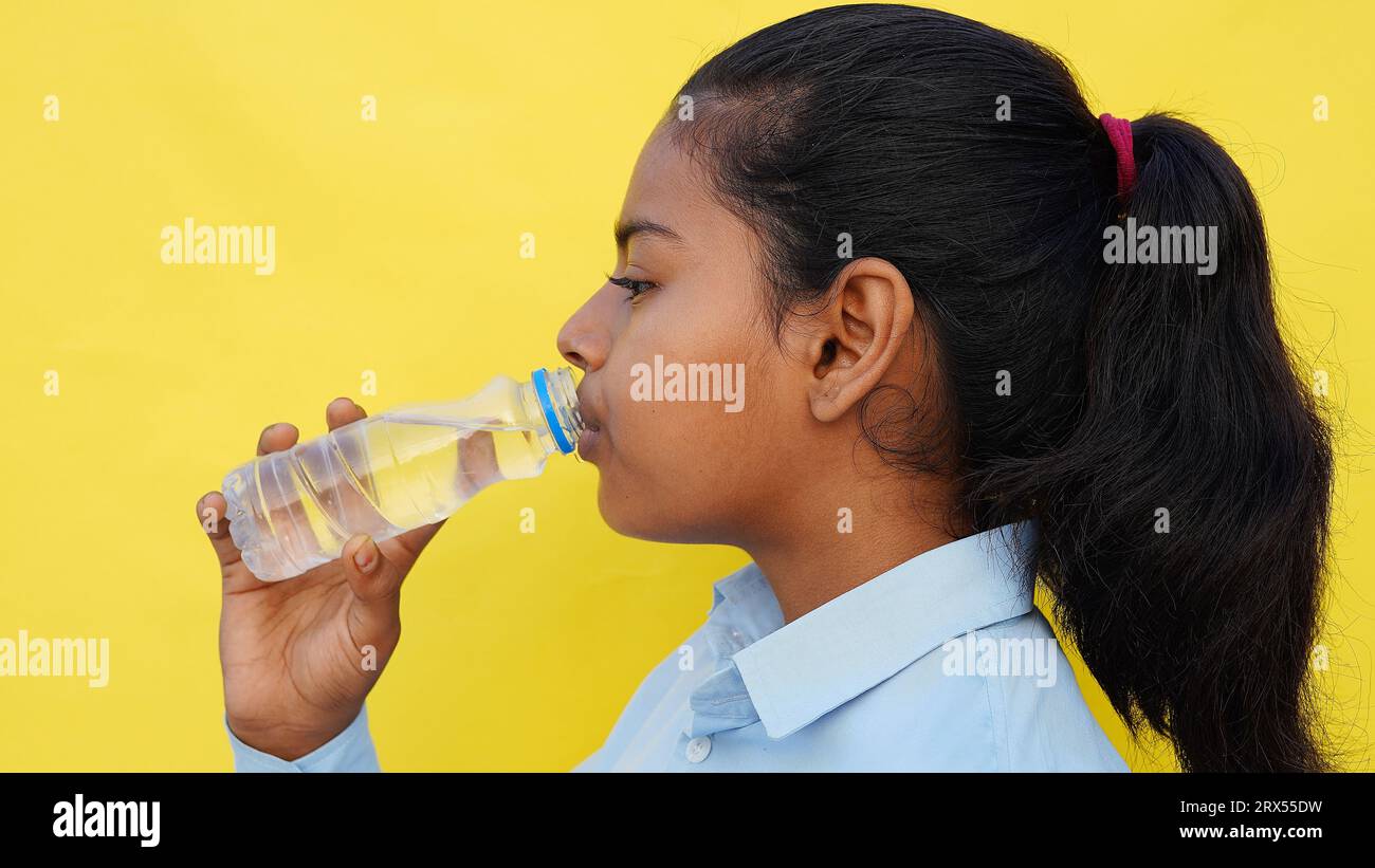 Asian school kids drink water from a bottle against the studio ...