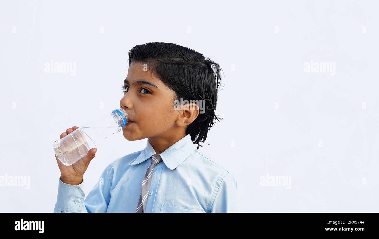 Asian school kids drink water from a bottle against the studio ...