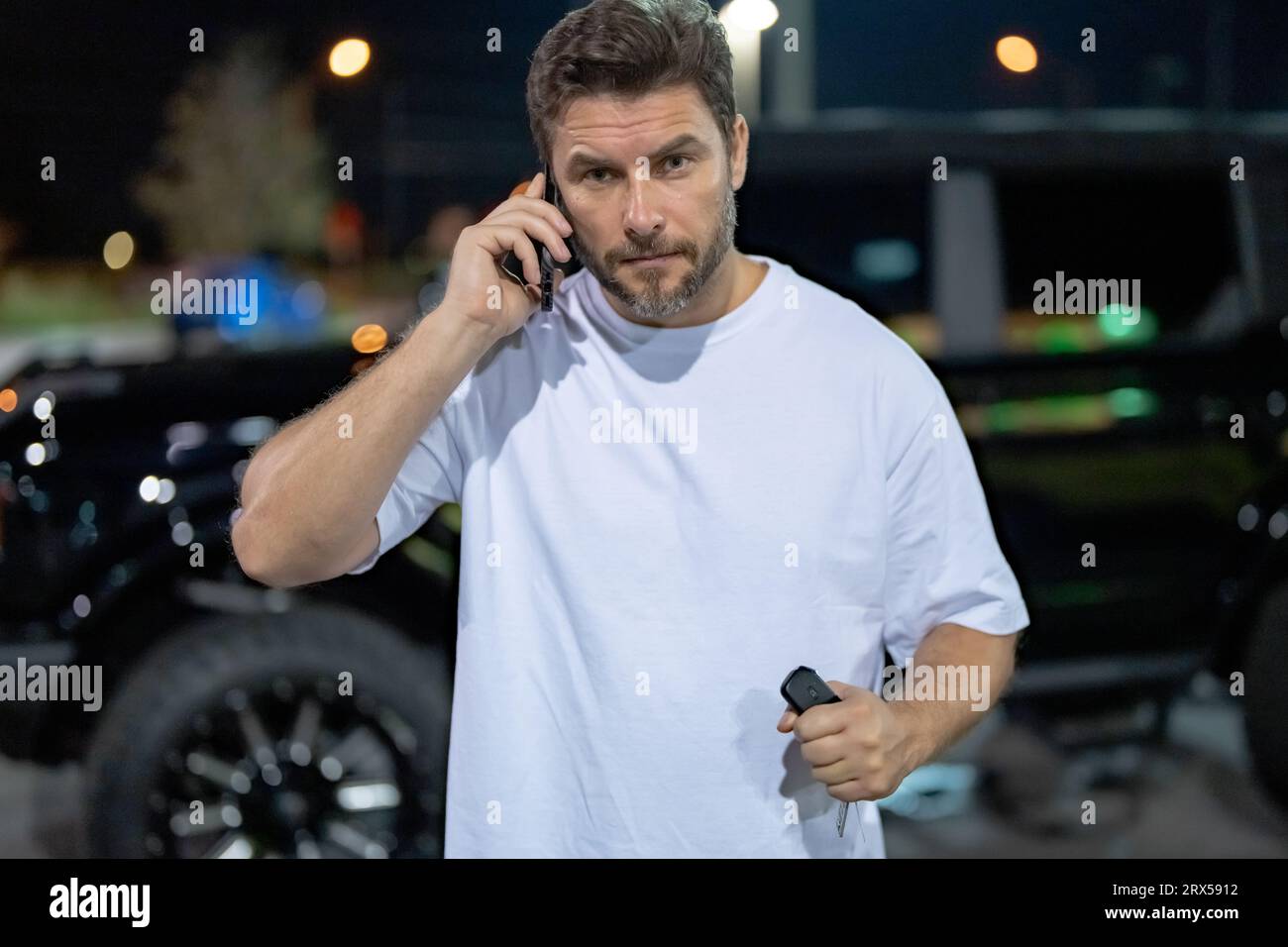 Gangster, criminal concept. Angry man near car on night urban street ...