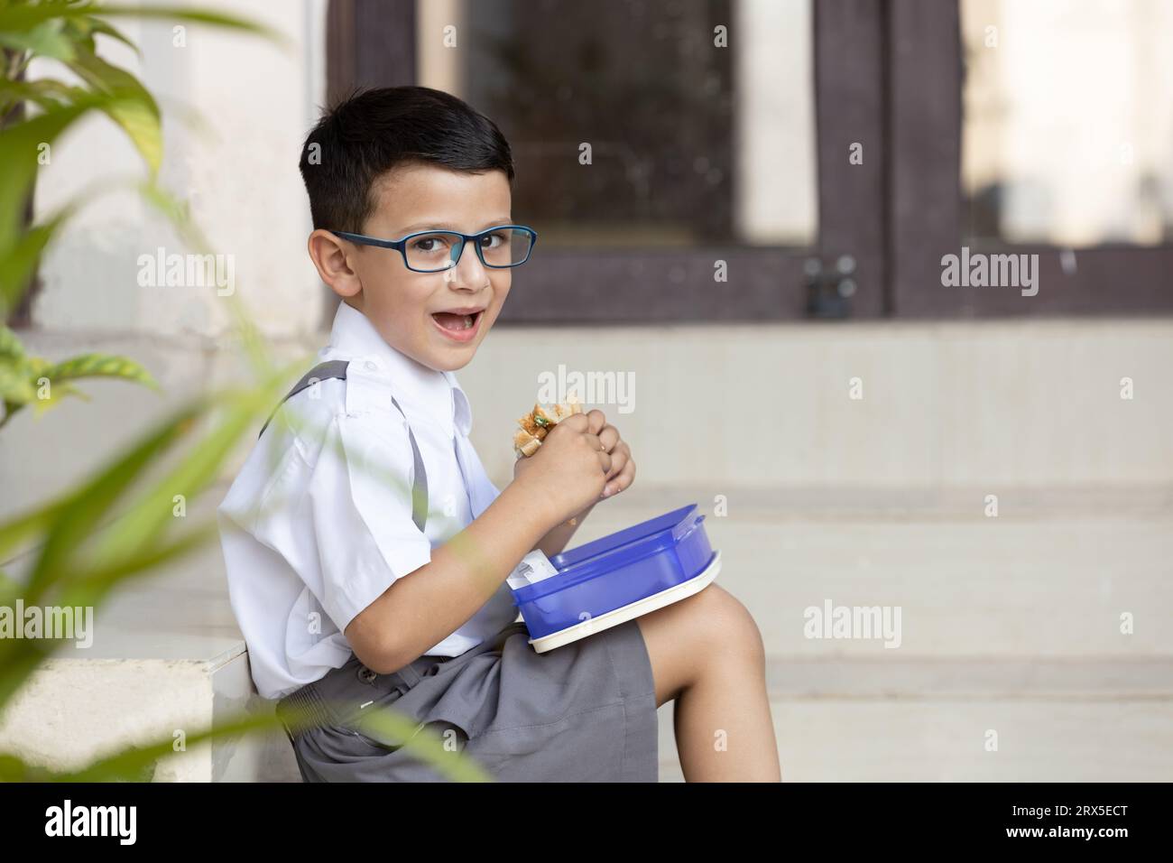 Indian boy school child resting sitting take out a lunch box and having ...