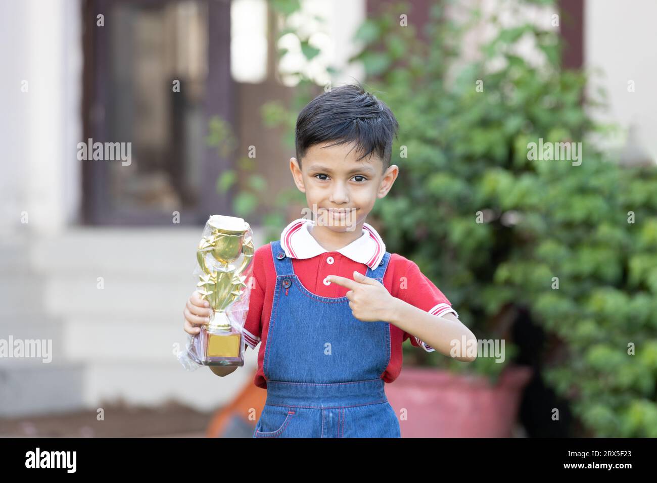 Happy Indian student schoolboy wearing school uniform holding victory ...